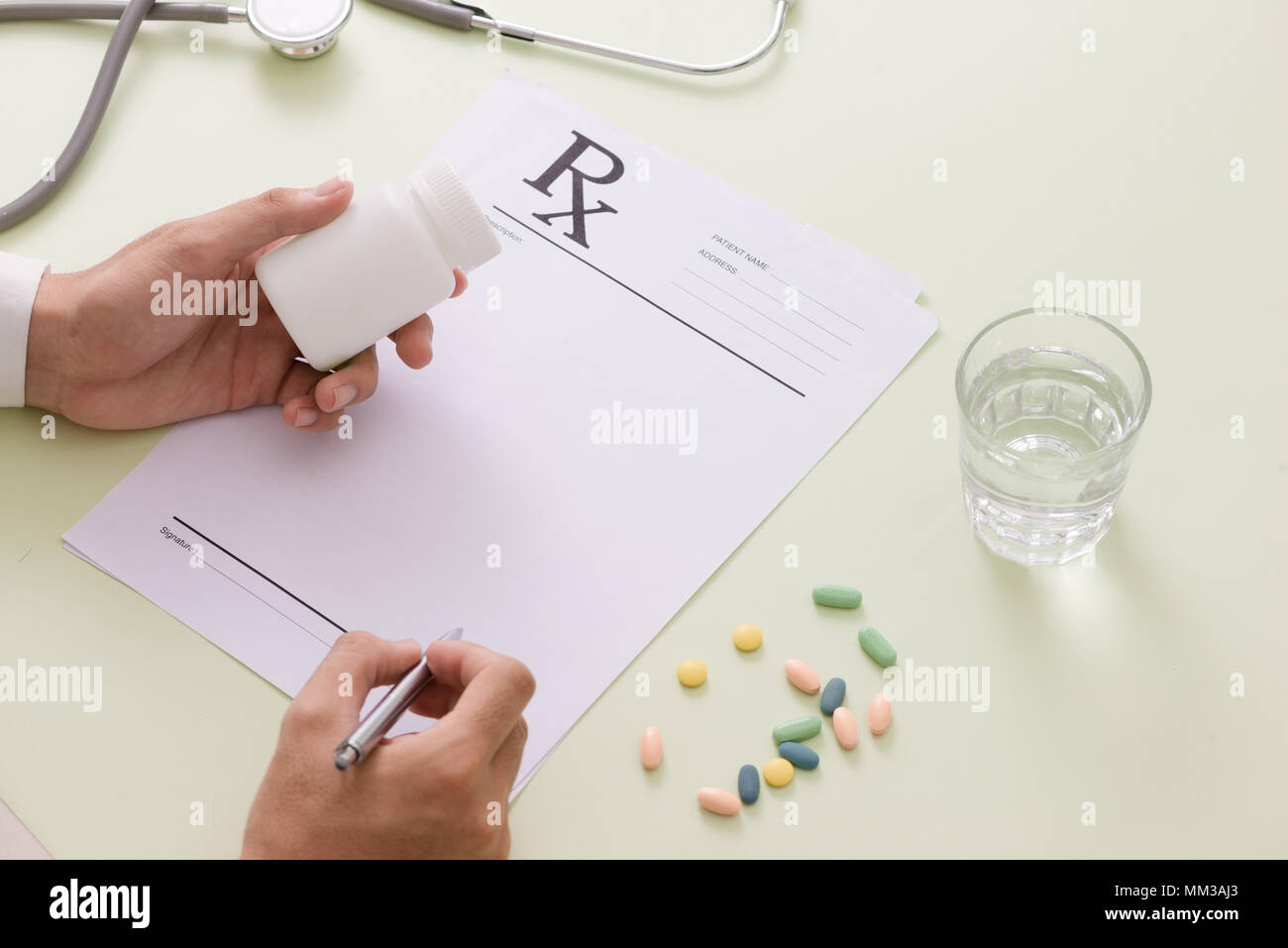 Top view of a doctor's hand writing a prescription. A pill bottle and ...