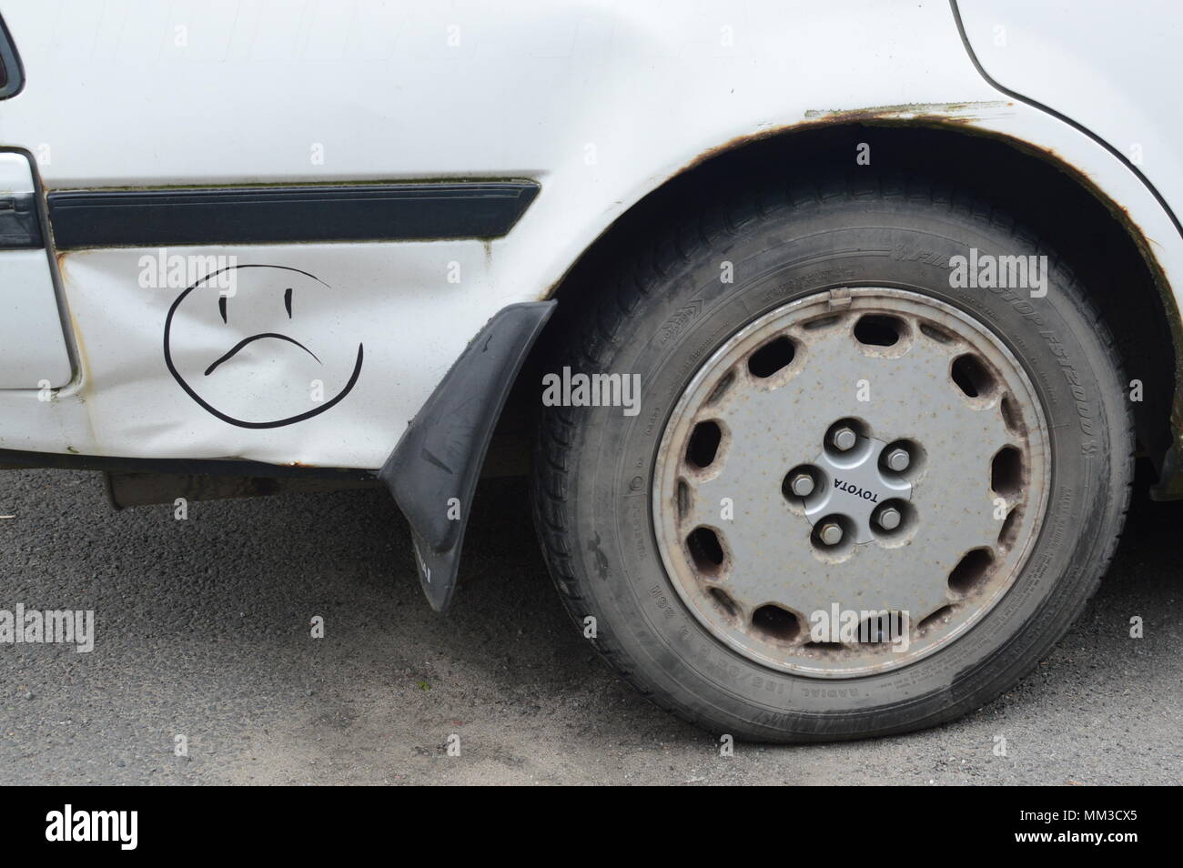 Dent in car - owner has drawn on a frowning face to show pain Stock ...