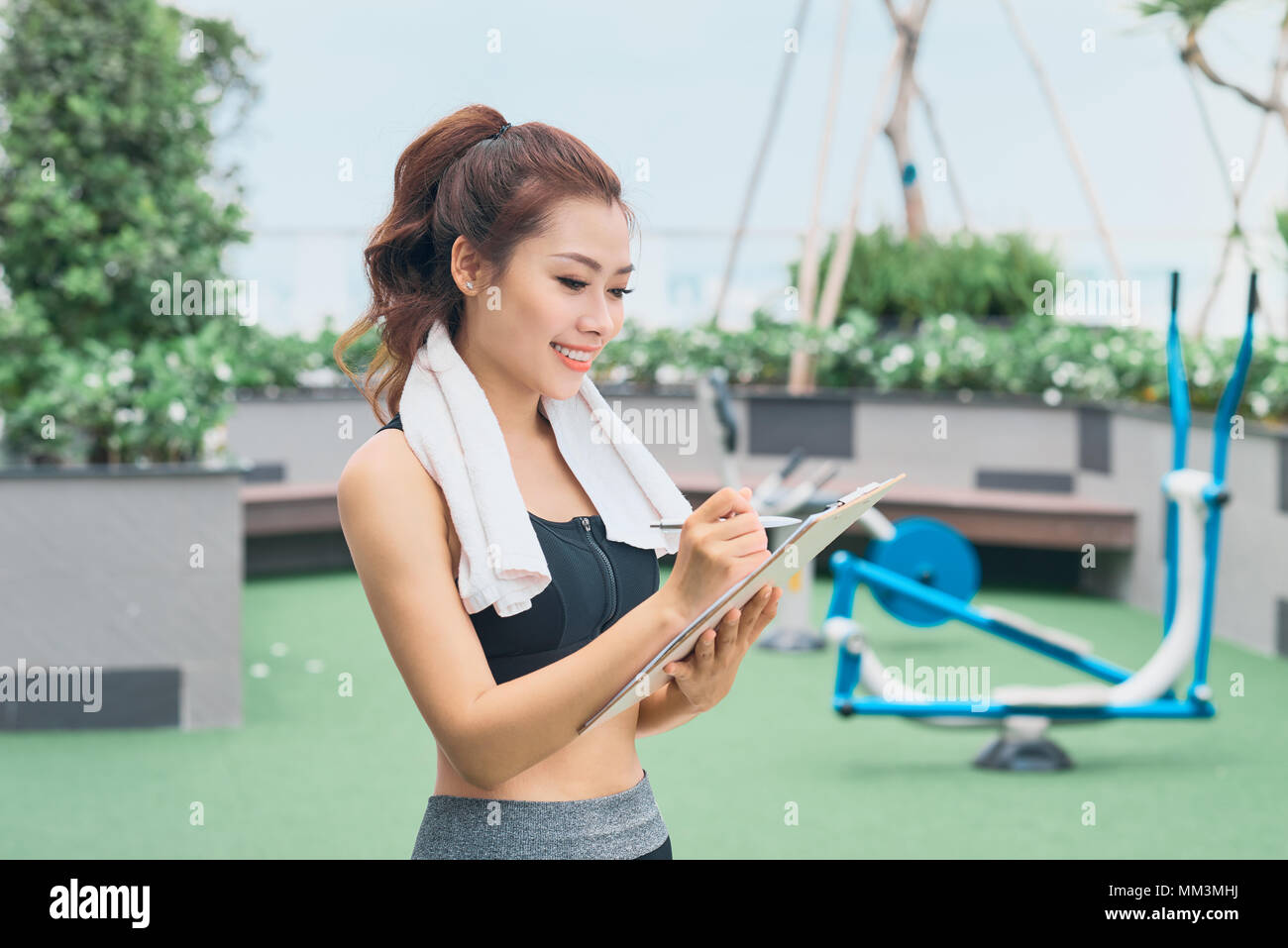 Young female asian trainer taking notes outdoors Stock Photo - Alamy