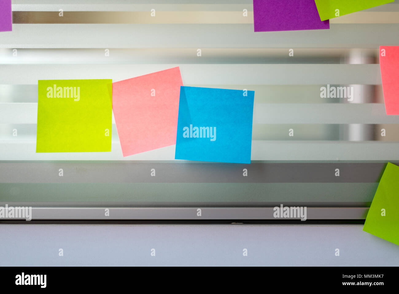 Randomly scattered blank colored sticky notes over glass screen of a ...