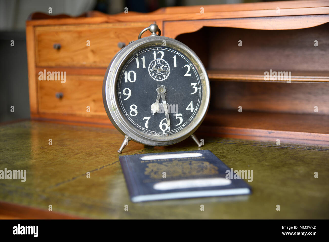 antique desk with alarm clock and british passport, name blanked out ...