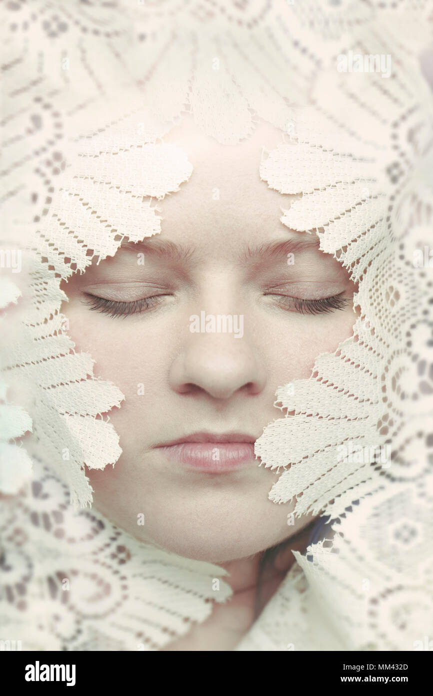 beautiful young caucasian womans face surrounded by white lace , closed ...