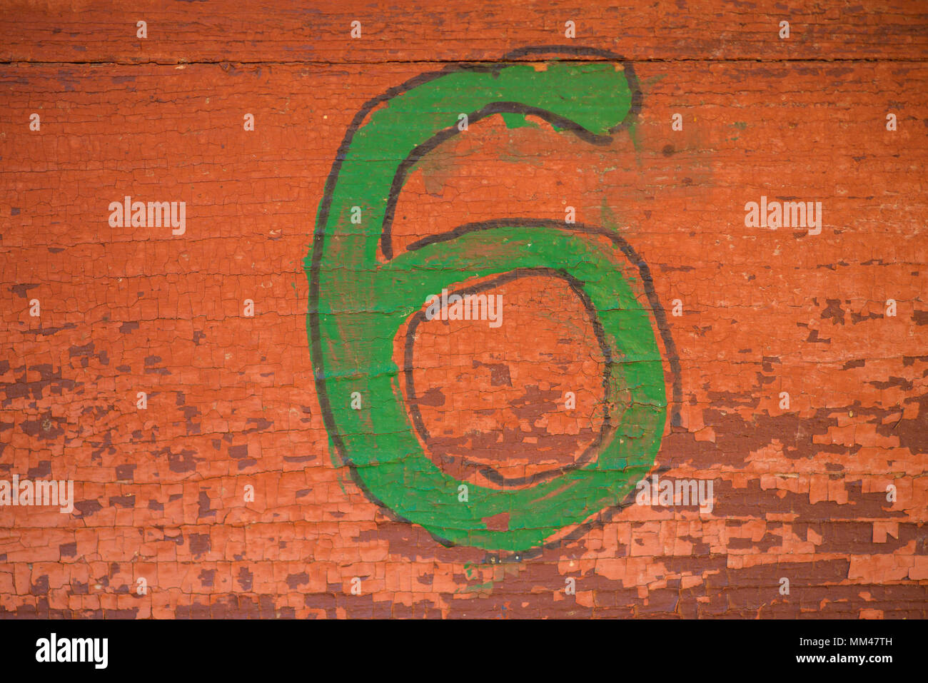 Green number six on a brown wall texture for a background. Old peeling ...