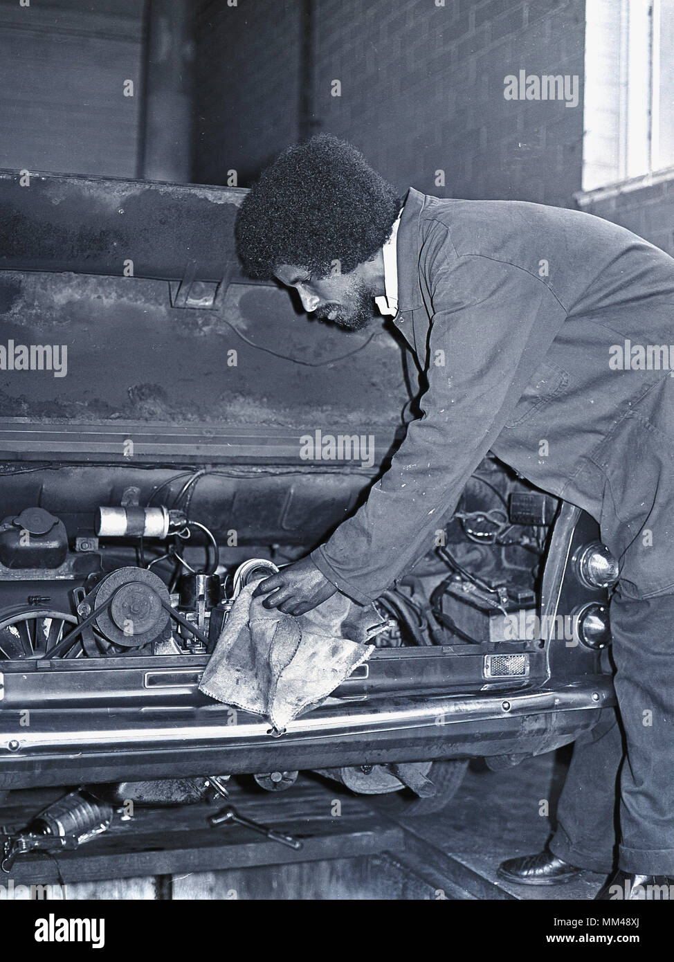 1970s, adult male car mechanic working on the engine of a motor vehicle ...