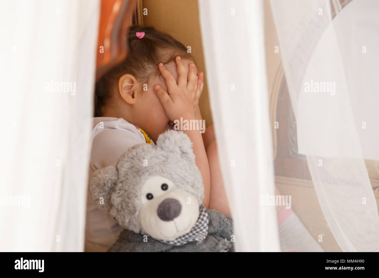 Little kid hiding behind teddy bear Stock Photo - Alamy