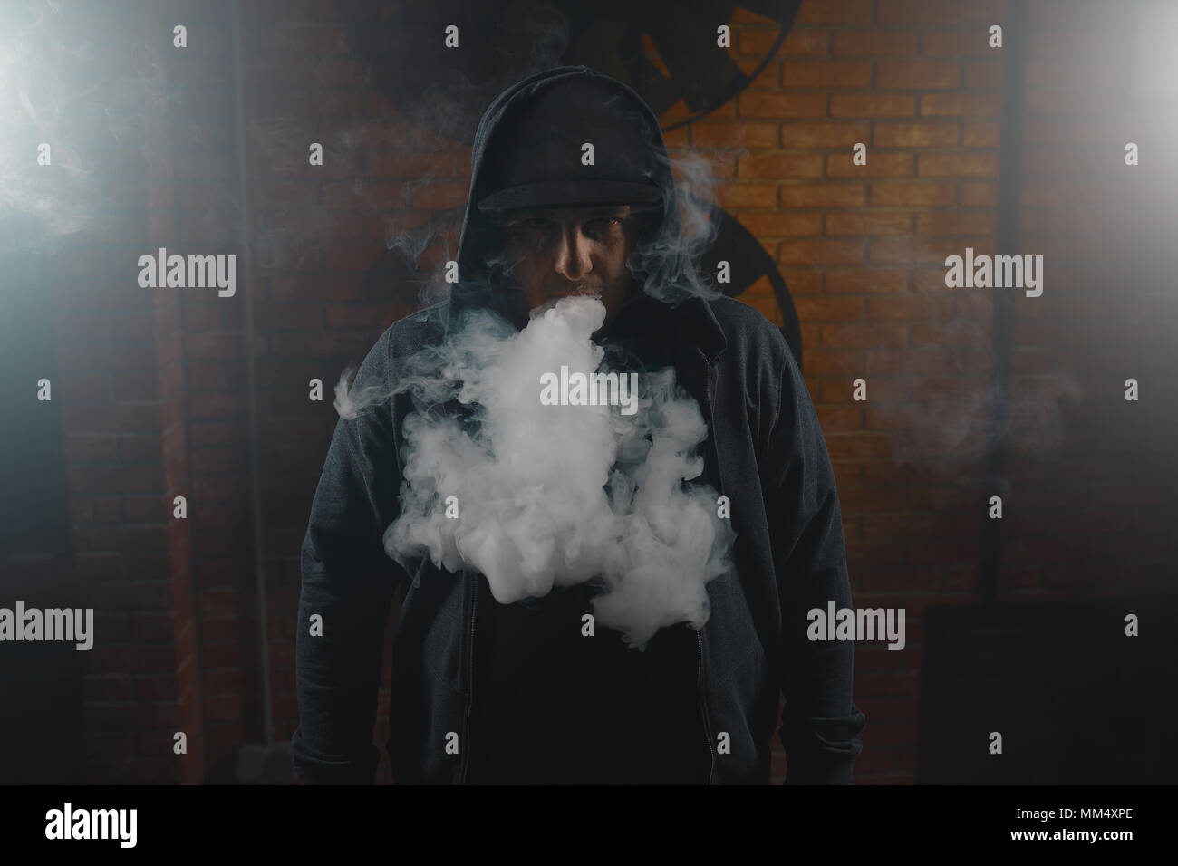 A cloud of vapor. Vaping man holding a mod. Brick background. Vape ...