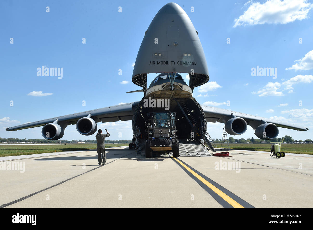 A loadmaster guides the positioning of a forklift coming off a C-5 M ...