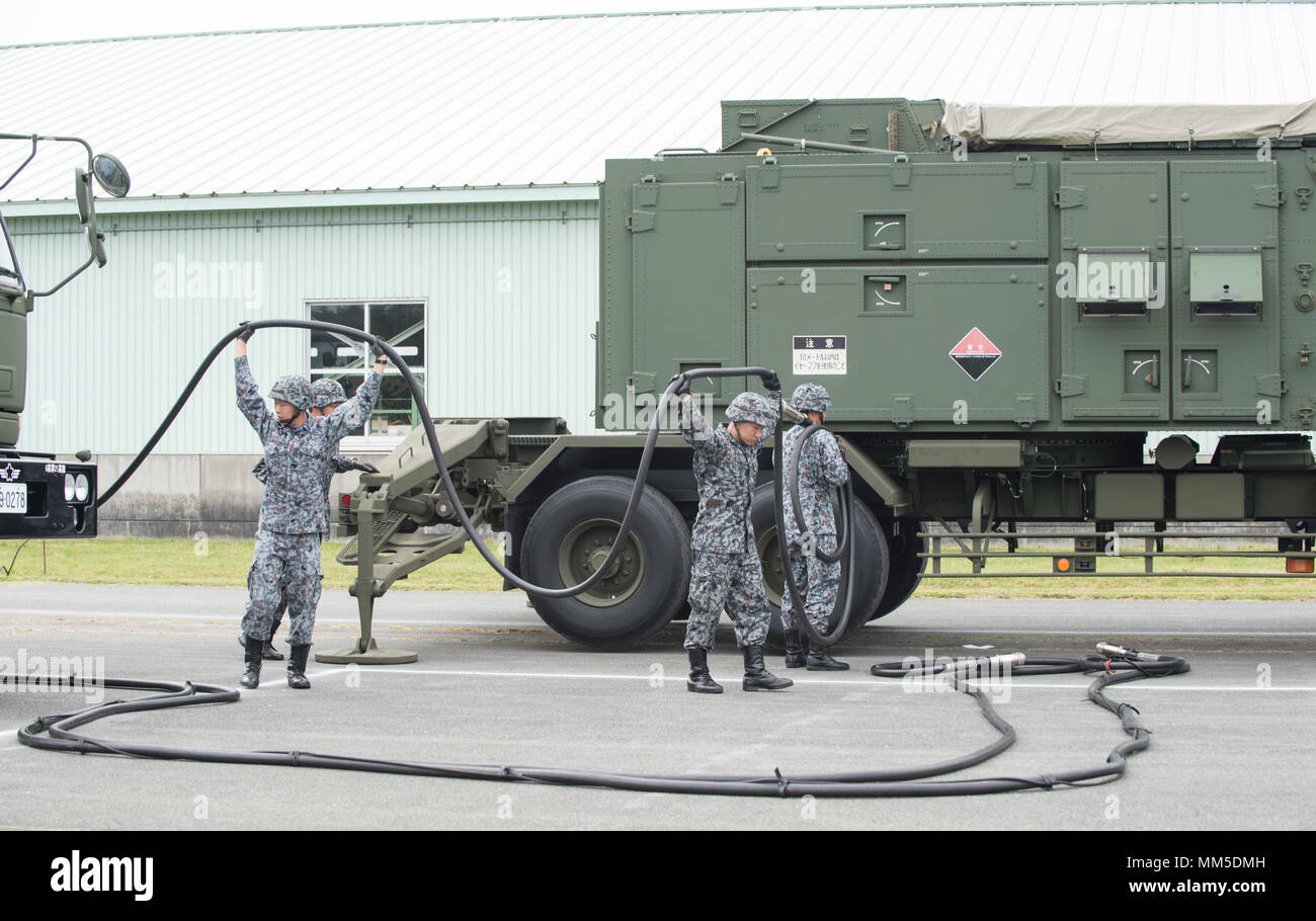 Japan Air Self-Defense Force service members bring a fuel line to a ...
