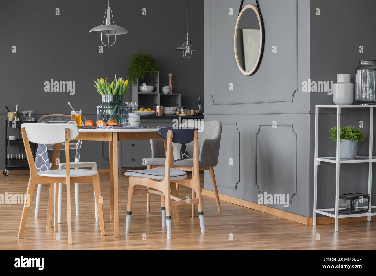 Side view of grey kitchen interior with a dining table, chairs, mirror ...