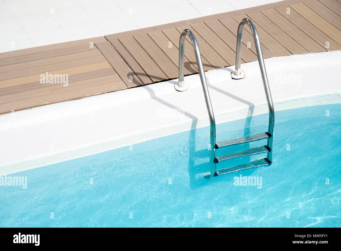 closeup of a lonely swimming pool outdoors, with a metallic ladder ...