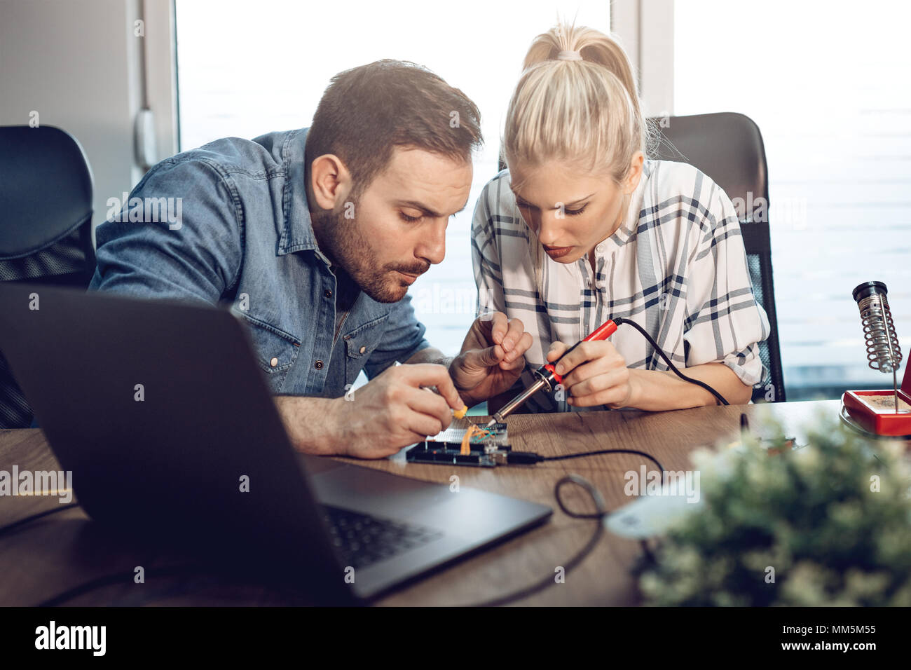 Two young colleagues technician focused on the repair of electronic ...