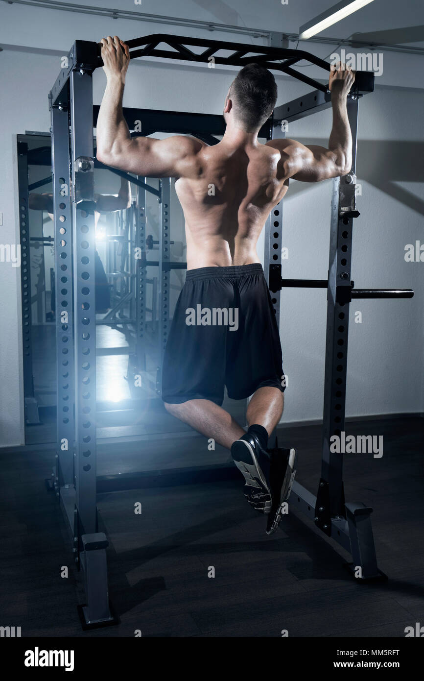 Man doing pull ups exercise in fitness studio Stock Photo - Alamy