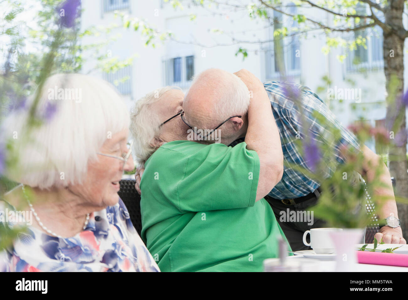 Senior people hugging on breakfast table Stock Photo - Alamy