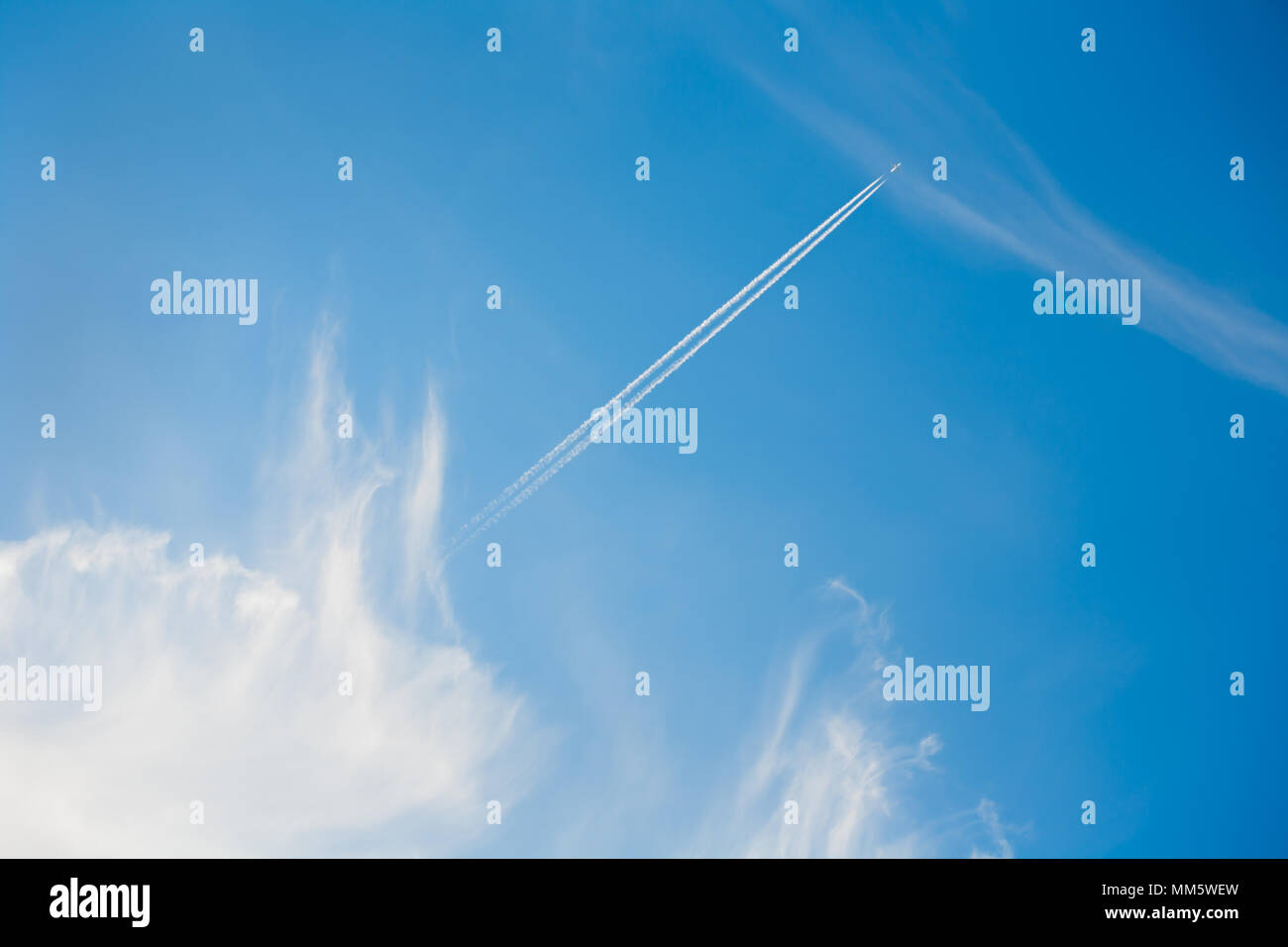 A jet plane draws an inversion trail in the sky Stock Photo - Alamy