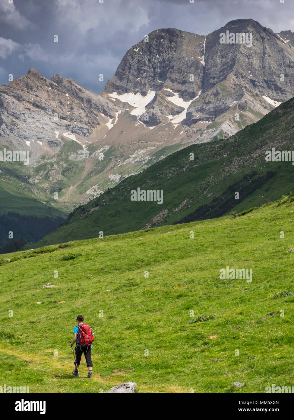 Woman hiking in the High Pyrenees descending Oulettes d'Ossoue towards ...