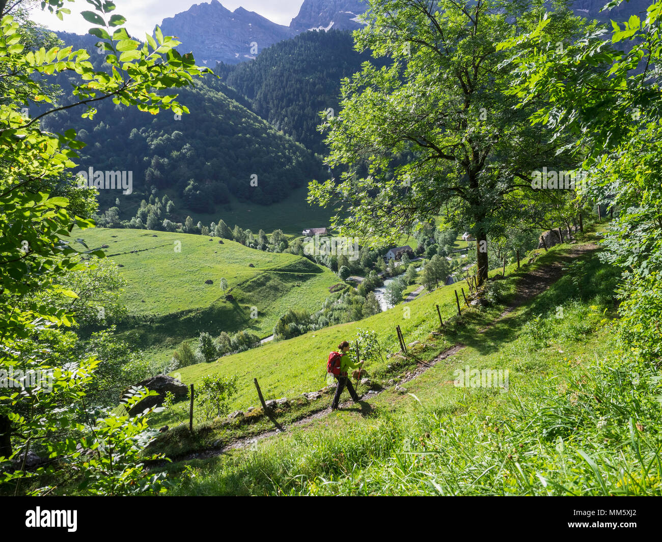 Woman hiking in the High Pyrenees on a single trail with view over ...