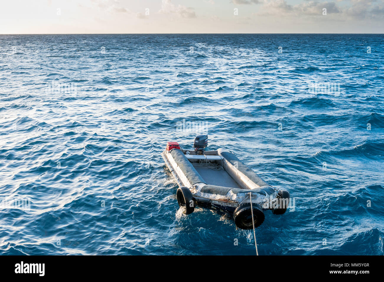 A small inflatable dinghy bobs on the water behind the live aboard ...