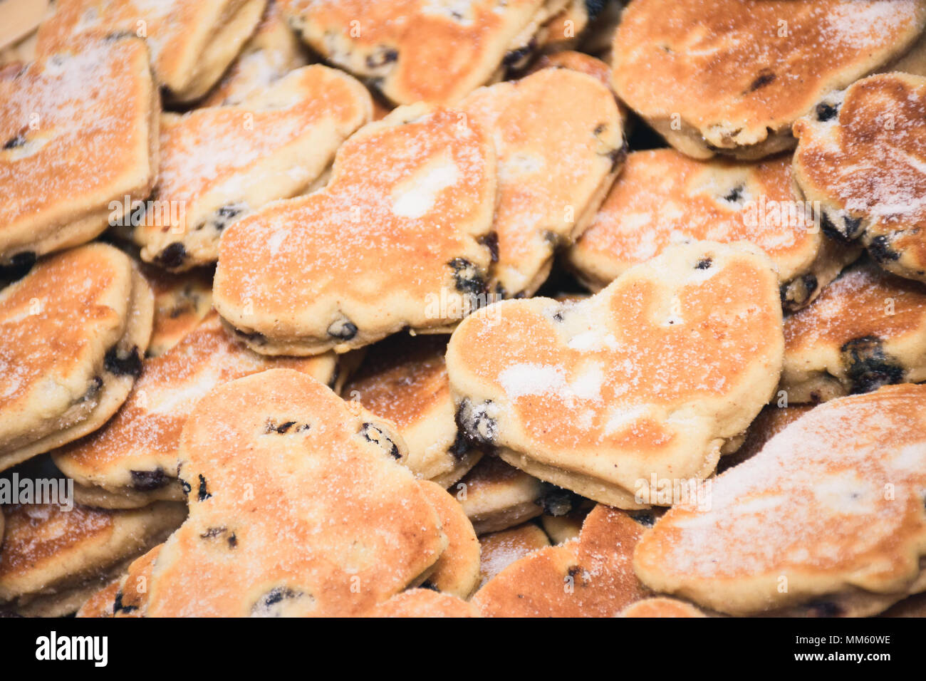 Traditional Welsh cakes with raisins and powdered sugar macro in heart ...