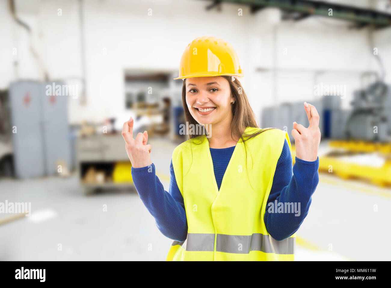 Young female engineer making good luck gesture with fingers crossed and ...