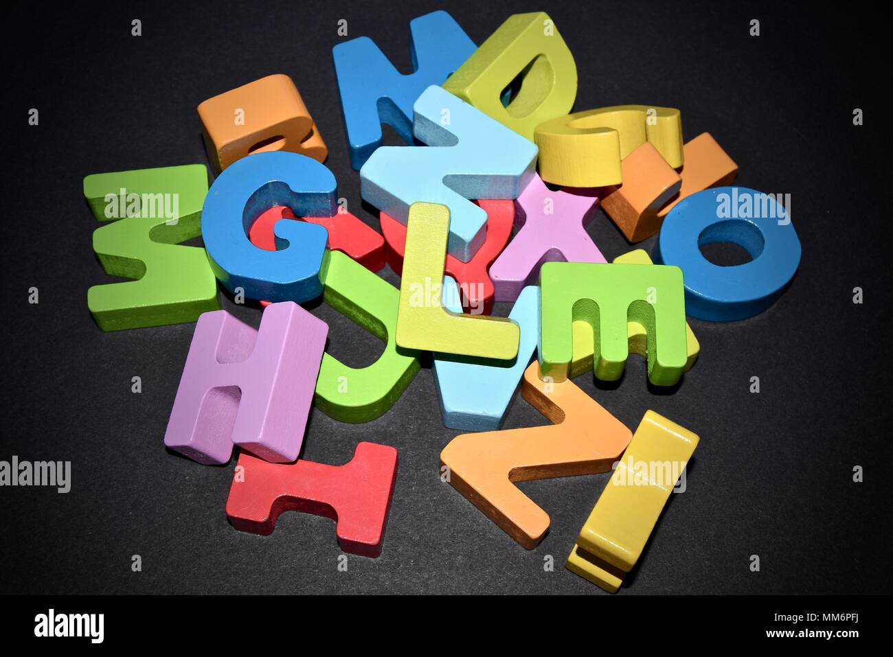 A pile up of multicoloured letters on a black background with focus on ...