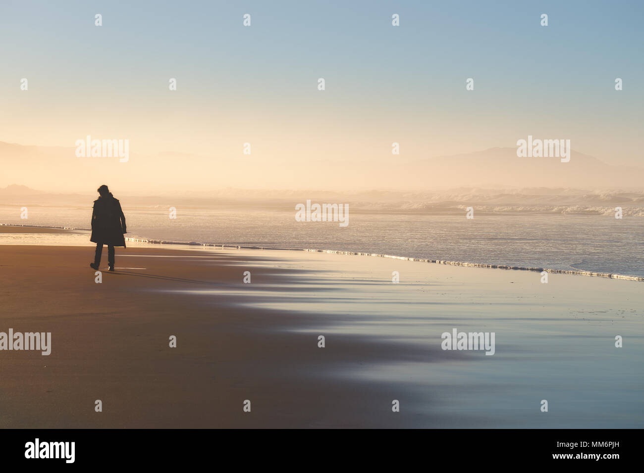 lonely person walking on beach at the sunset Stock Photo - Alamy