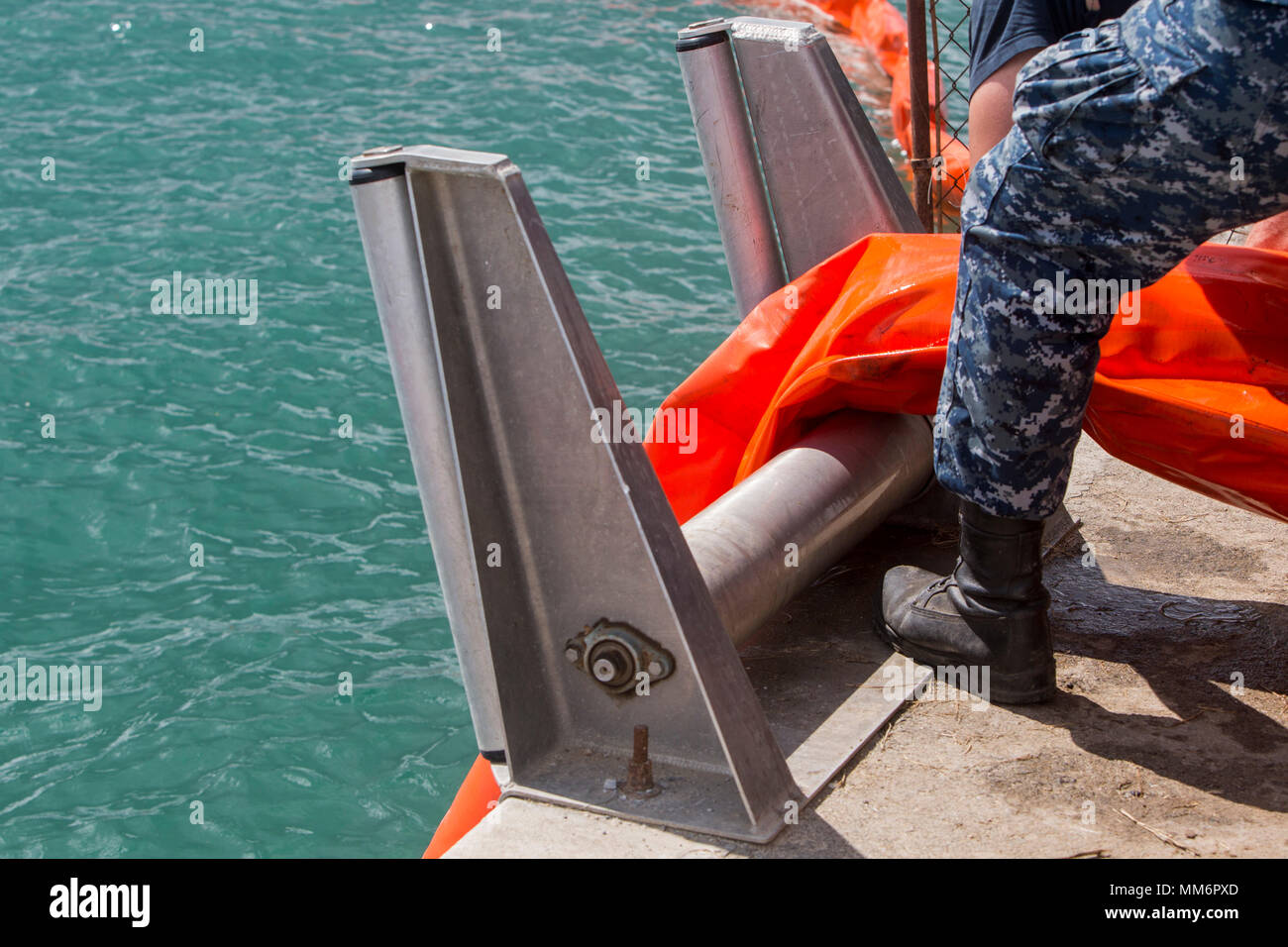 A U.S. Navy corpsman with Waterfront Operations pulls in a floating ...