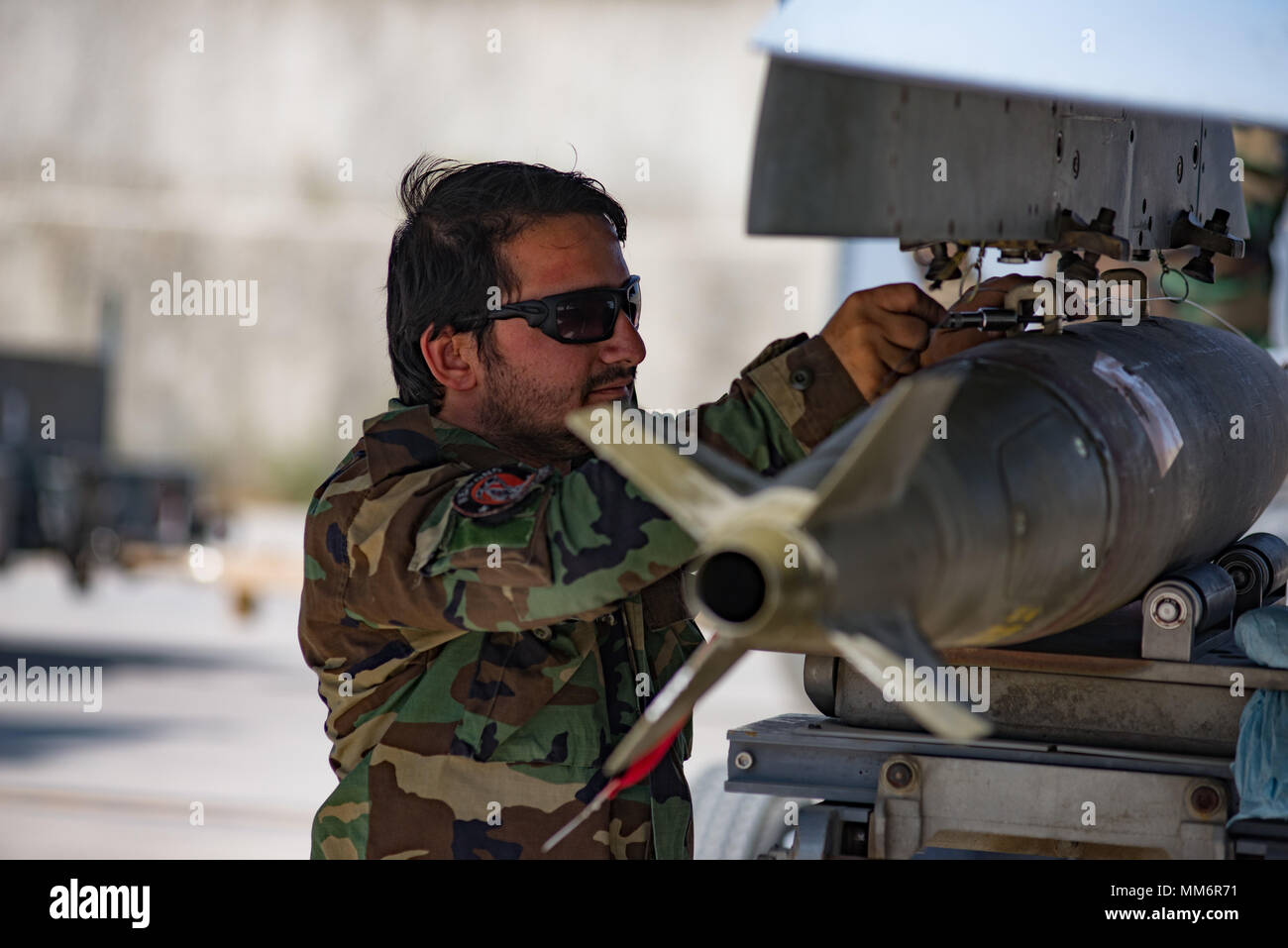 An Afghan Airman mounts an MK-81 bomb to the wing of an Afghan A-29 ...