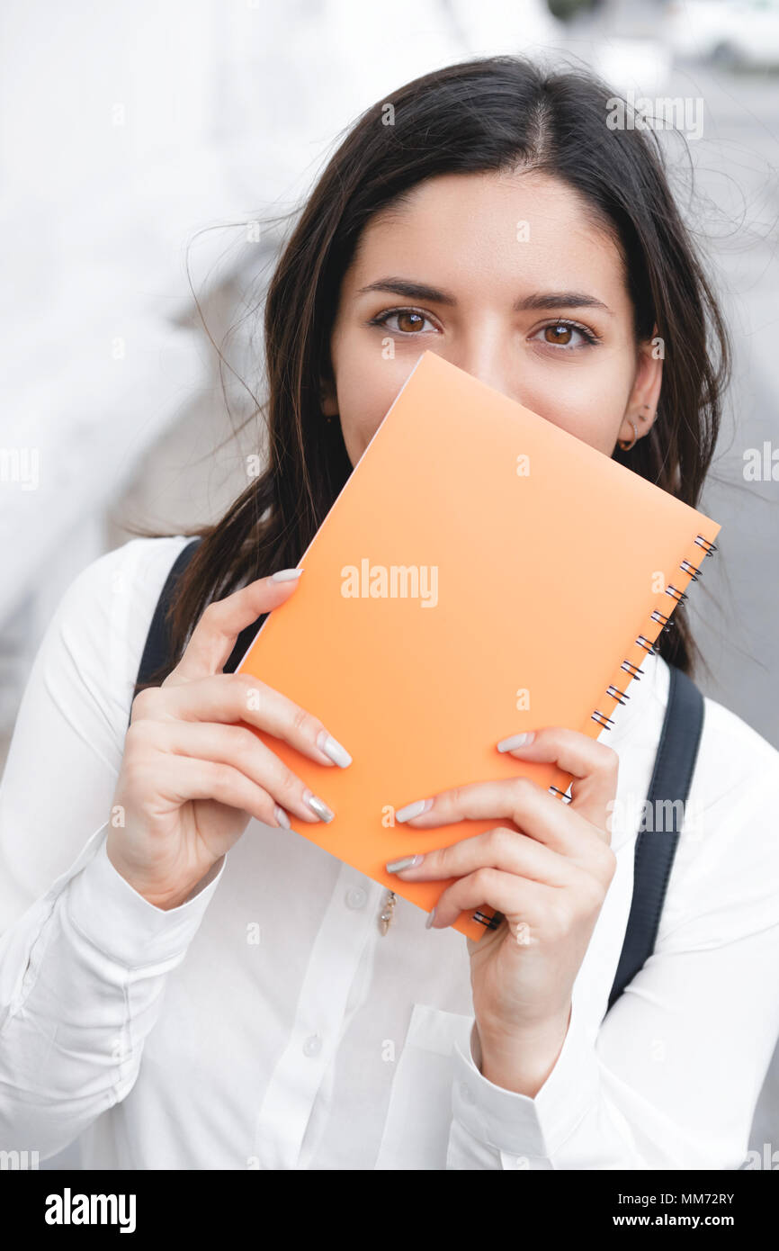 Female student holding a colorful notebook and smiling behind it Stock ...