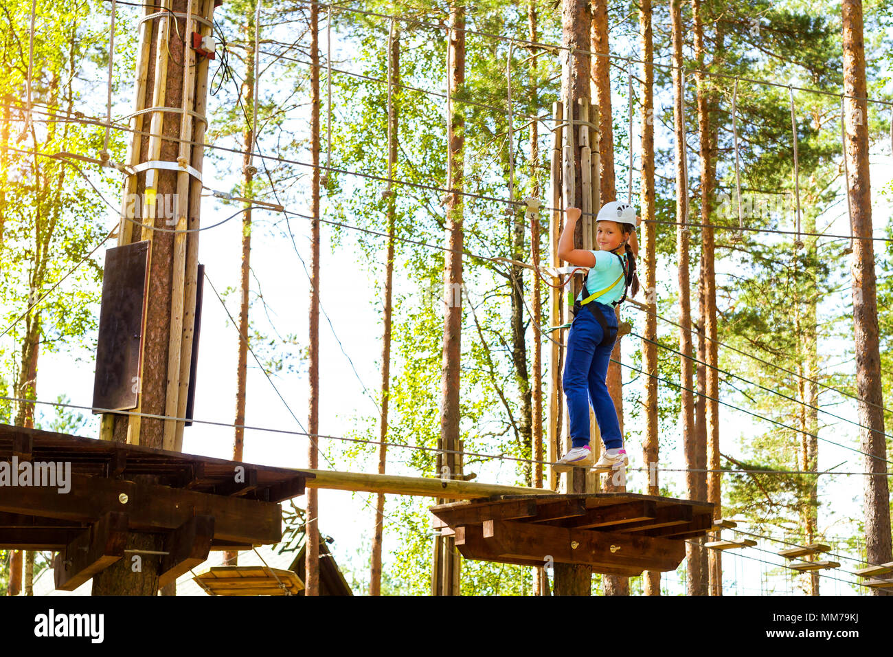 Teenage girl goes on hinged trail in extreme rope Park in summer forest ...