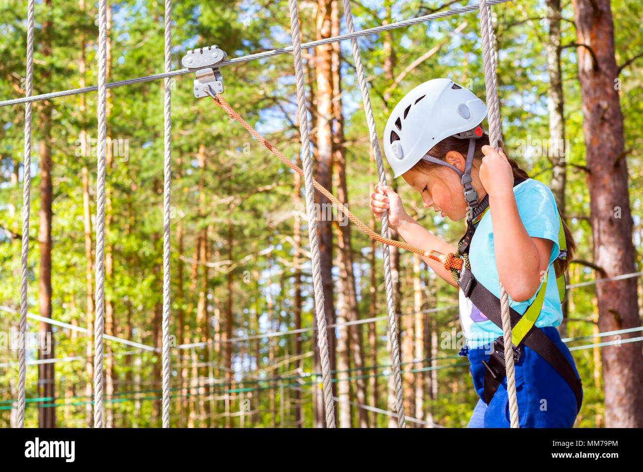 Teenage girl goes on hinged trail in extreme rope Park in summer forest ...