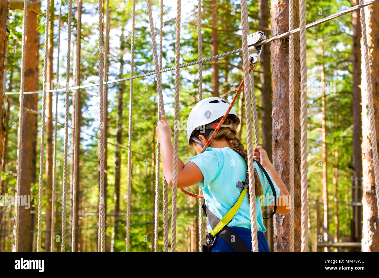 Teenage girl goes on hinged trail in extreme rope Park in summer forest ...