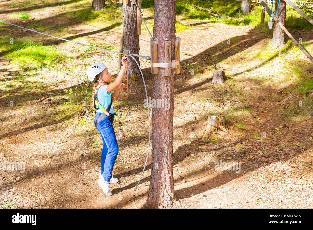 Teenage girl goes on hinged trail in extreme rope Park in summer forest ...