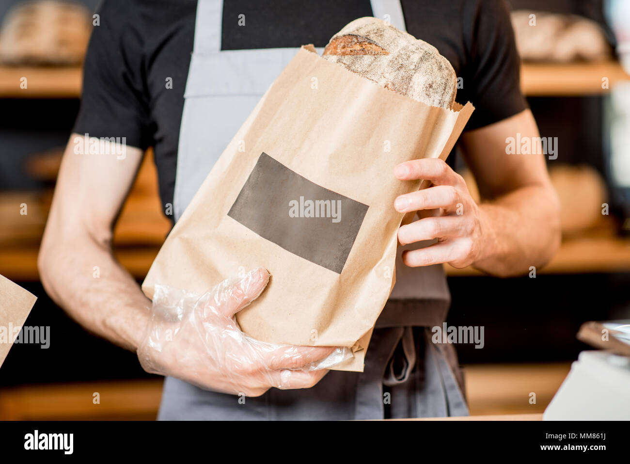 Packing bread into the paper bag Stock Photo - Alamy