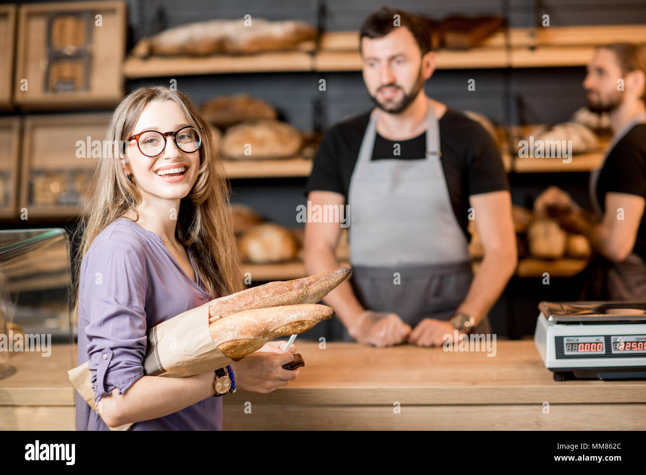 Woman buying bread in the bakery shop with man sellers Stock Photo - Alamy