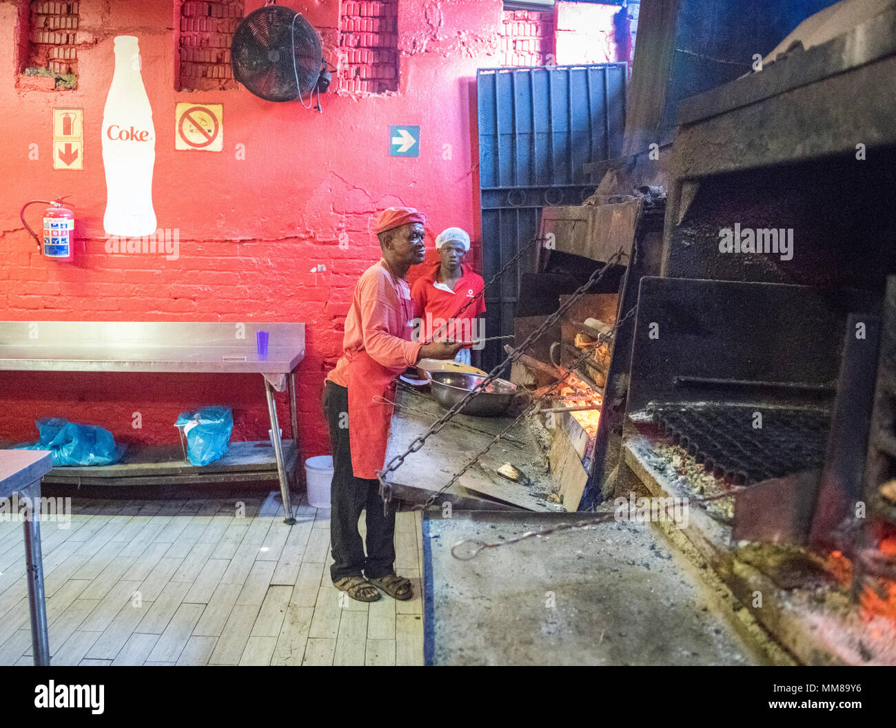 An African male chef grilling meat at Mzoli's in Cape Town, South ...