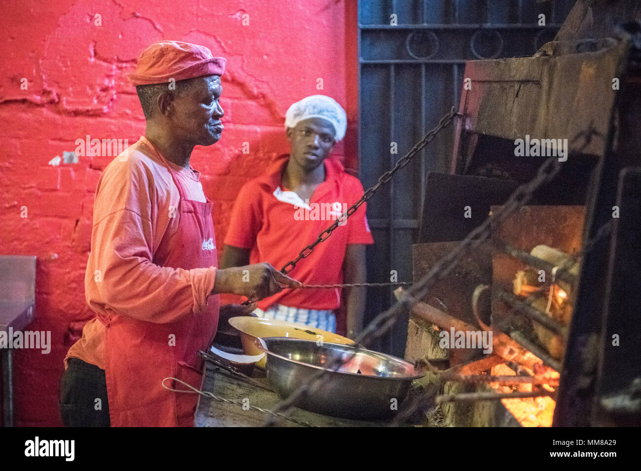 An African male chef grilling meat at Mzoli's in Cape Town, South ...