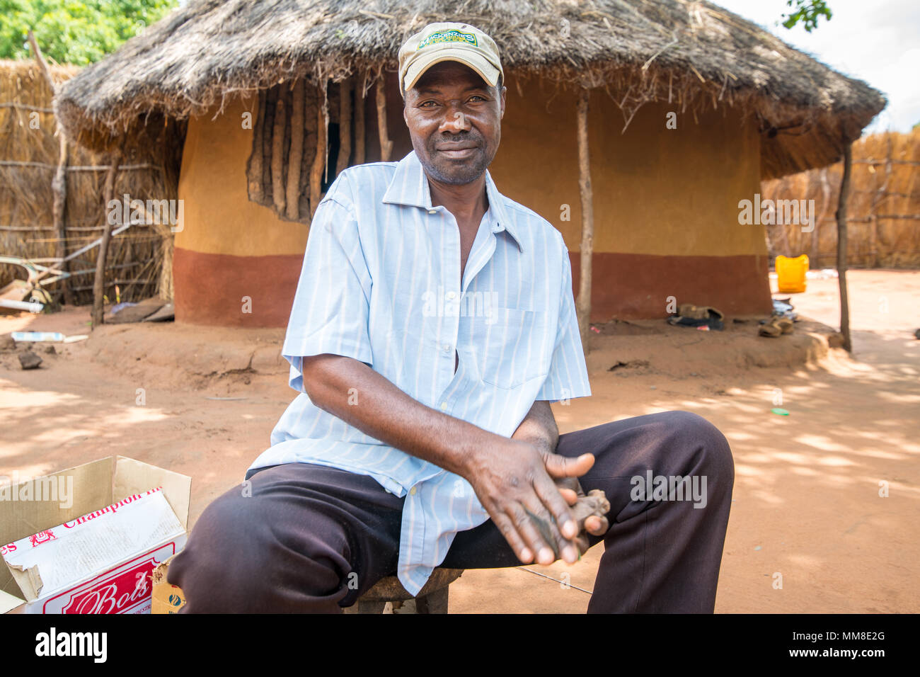 Portrait of Zambian man sitting and sanding to shape wooden ...