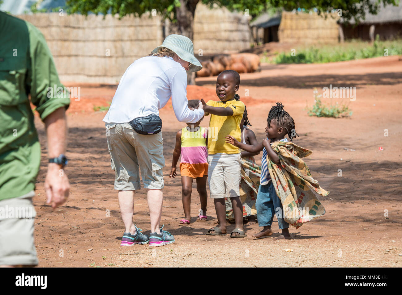 Group of young Zambian children extend their arms out with joy to ...
