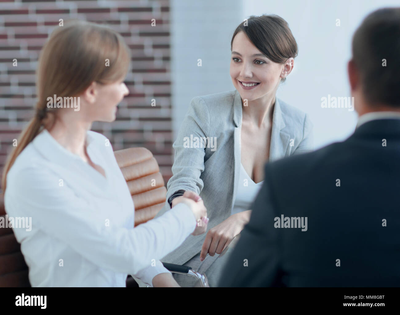 handshake of a Manager, and a client sitting behind a Desk.concept of ...