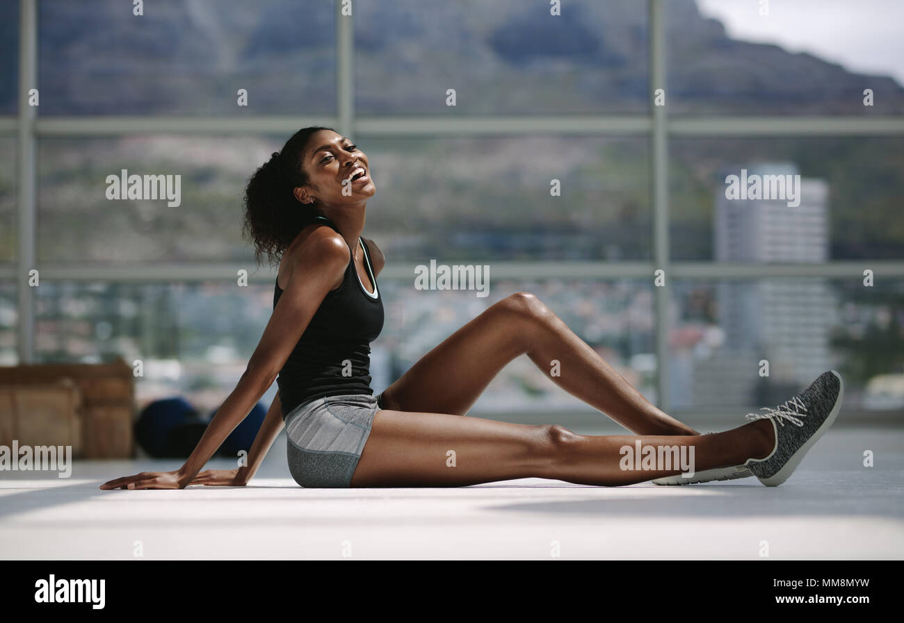 African woman sitting and relaxing after her workout at gym. Smiling ...