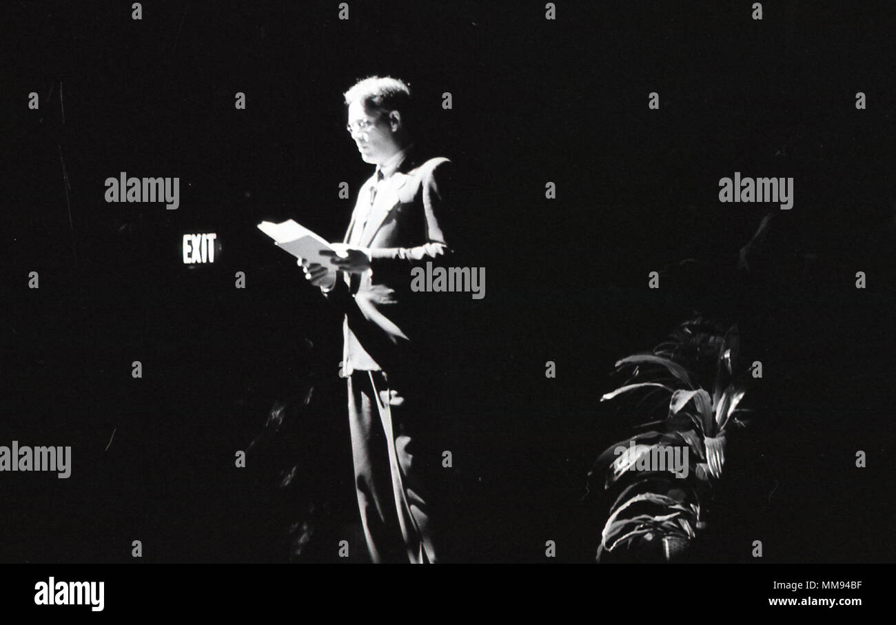 Snapshot of a man on stage, reading a script Stock Photo - Alamy