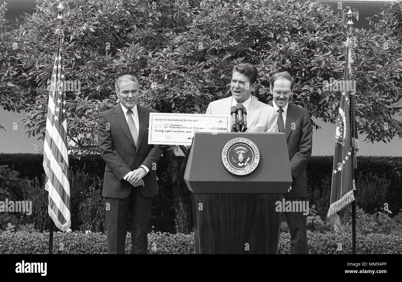 RONALD REAGAN AT THE PODIUM WIITH A CHECK IN HIS HANDS WITH TWO OTHER ...