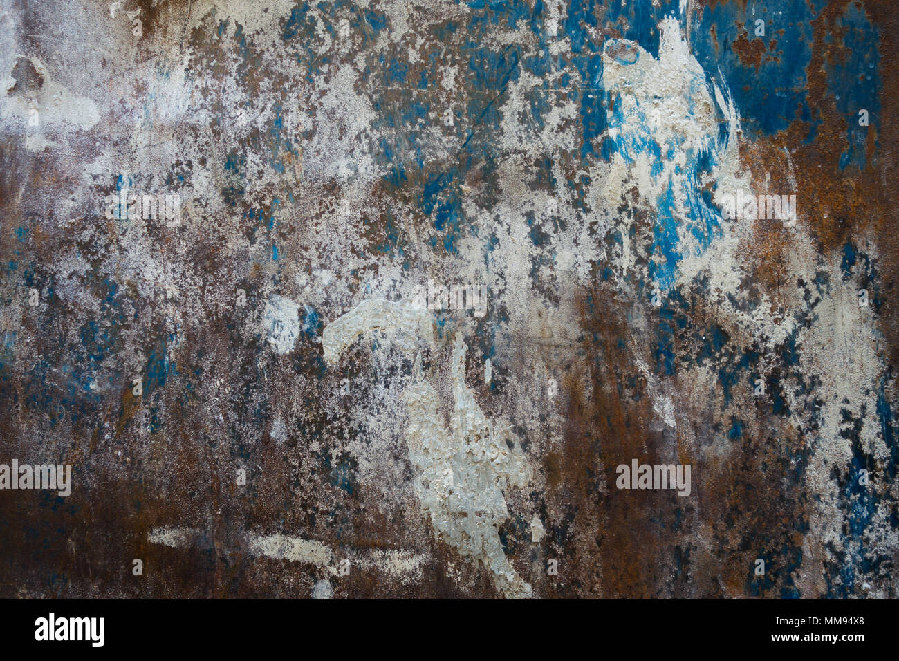 A textured pattern of white paint and brown rust on a blue metal ...