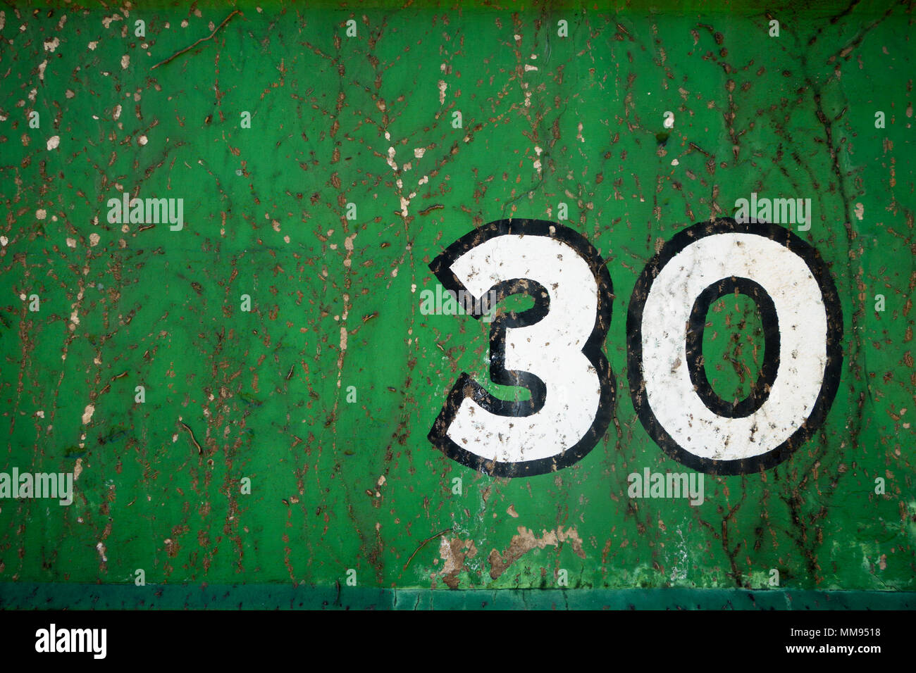 A vine covered green wall with the number 30 painted on it Stock Photo ...