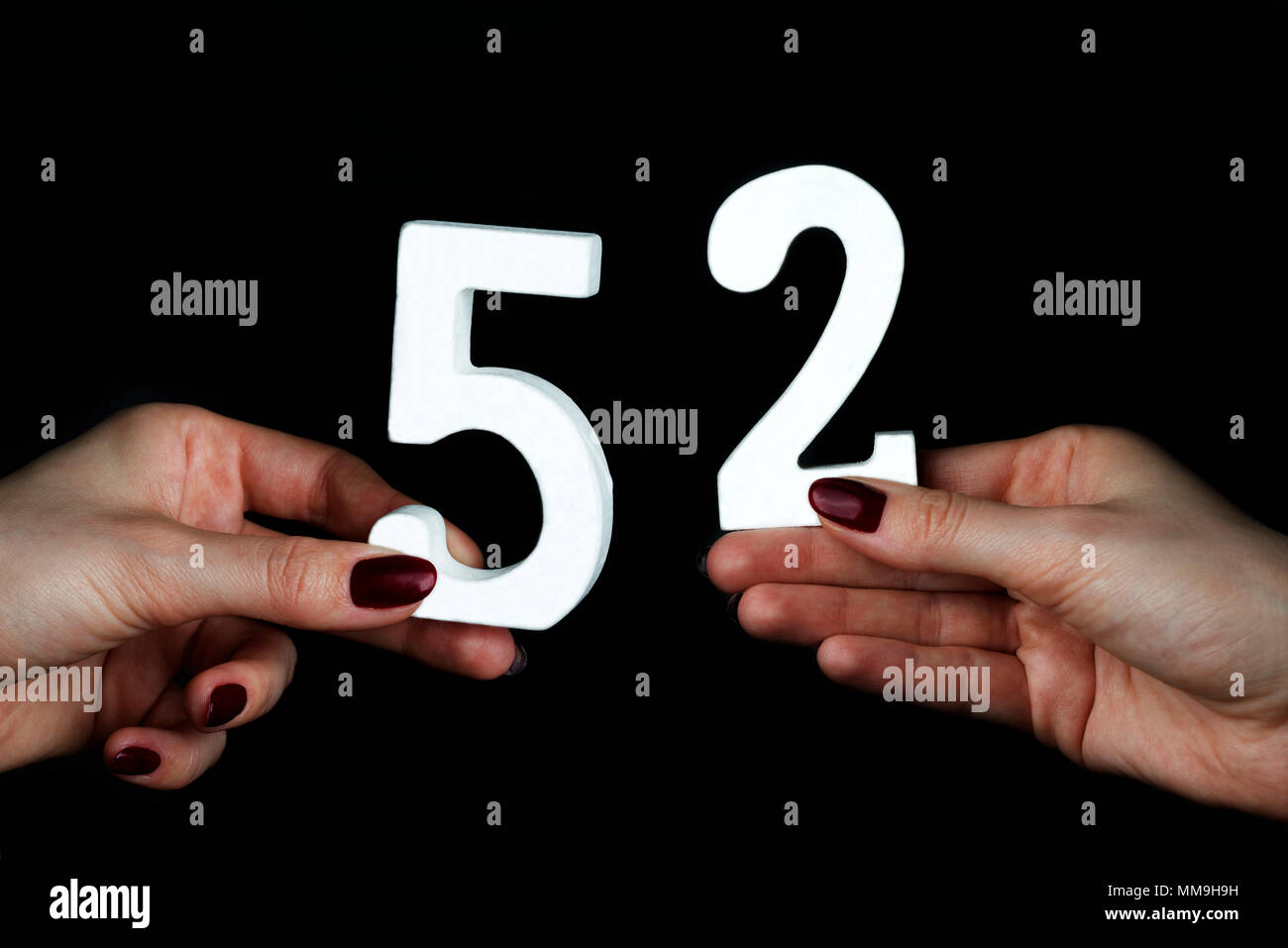 On a black background, female hand with number fifty-two Stock Photo ...