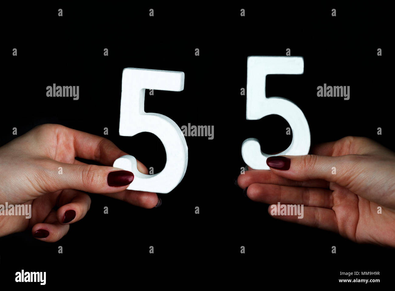 On a black background, female hand with number fifty-five Stock Photo ...