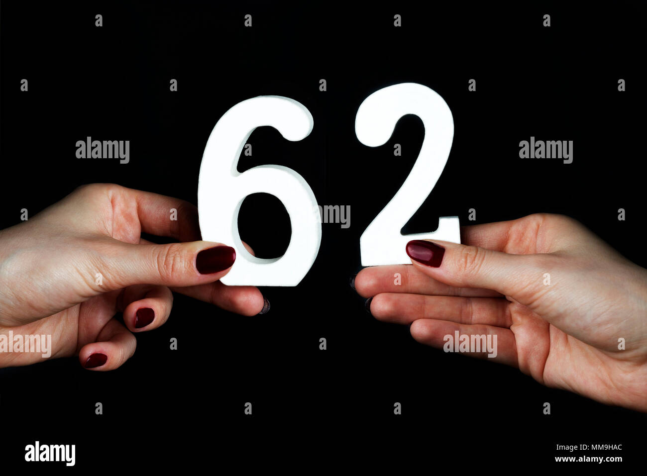 On a black background, female hand with number sixty-two Stock Photo ...