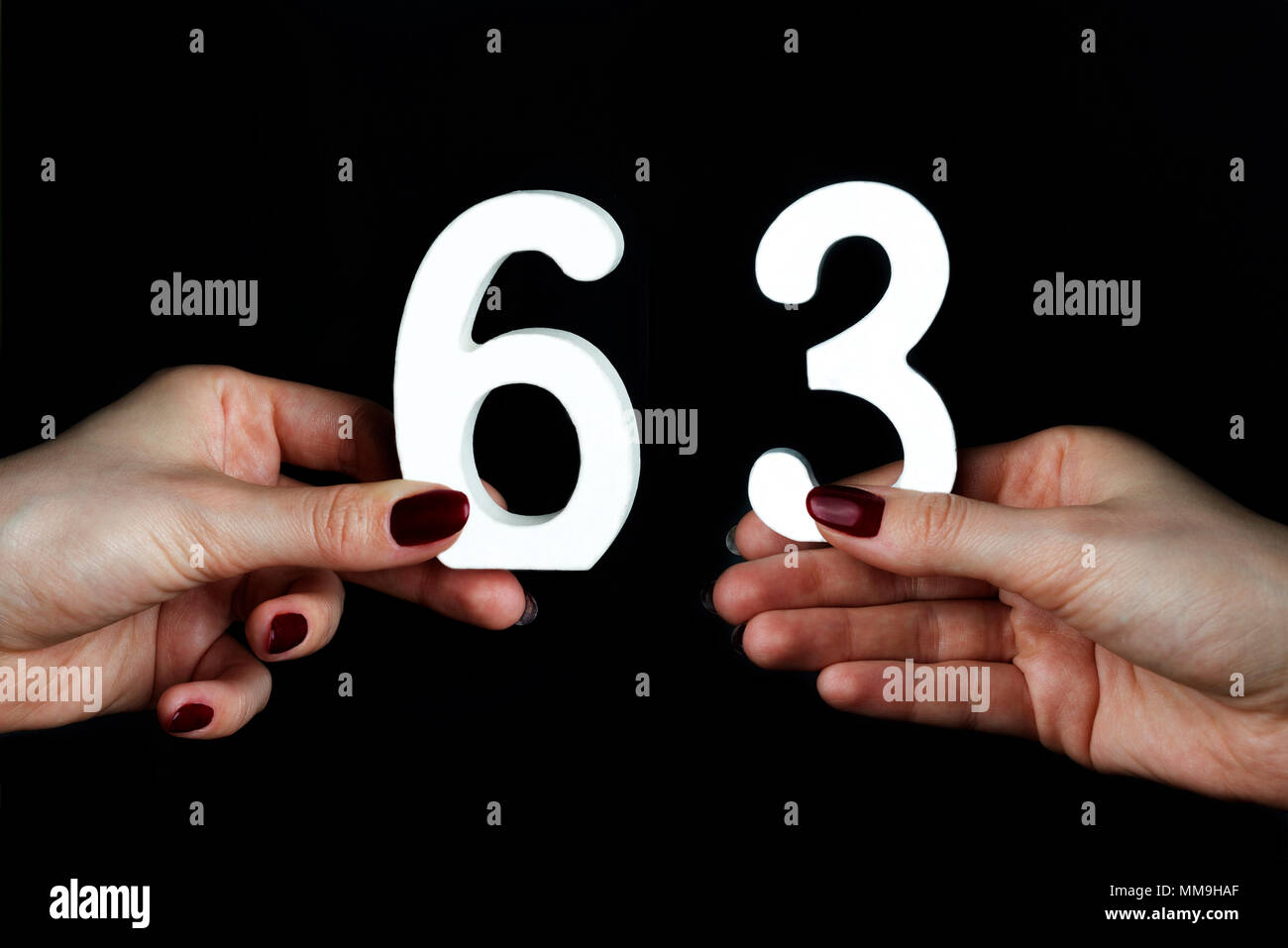 On a black background, female hand with number sixty-three Stock Photo ...