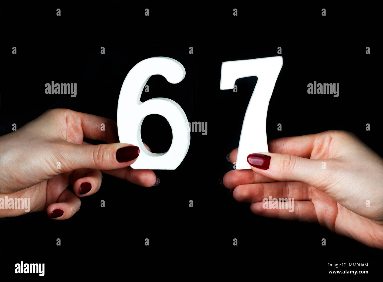 On a black background, female hand with number sixty-seven Stock Photo ...