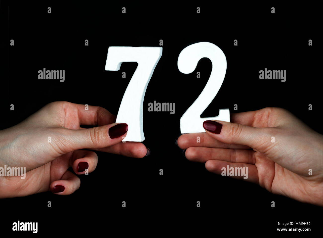 On a black background, female hand with numbers seventy-two Stock Photo ...